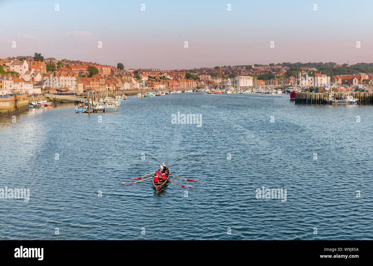Whitby harbour and marina in the evening light. A rowing boat with a ...