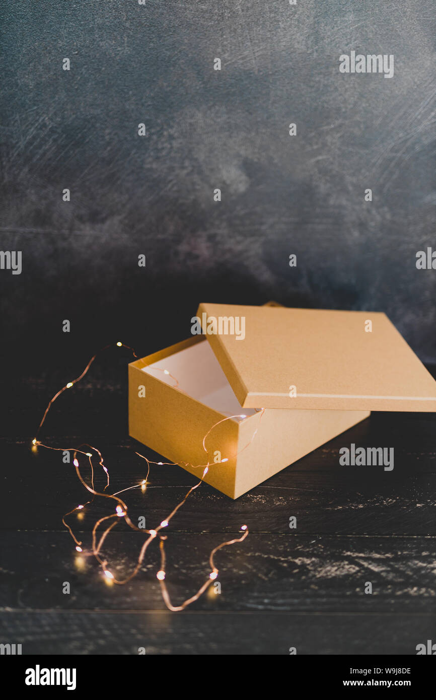 open mystery box or parcel with fairy lights popping out of it on dark ...
