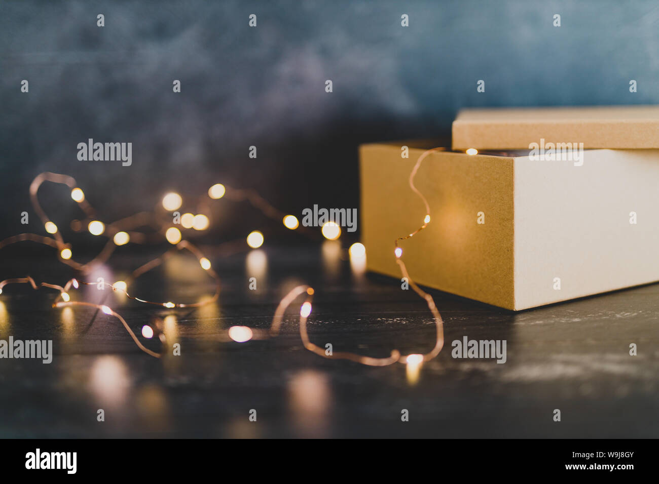 open mystery box or parcel with fairy lights popping out of it on dark ...