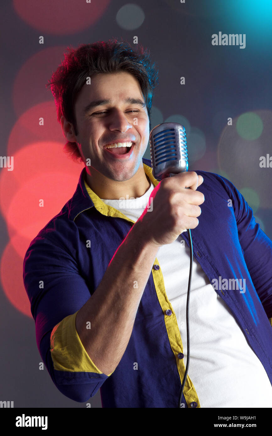 Man singing into microphone and smiling Stock Photo - Alamy