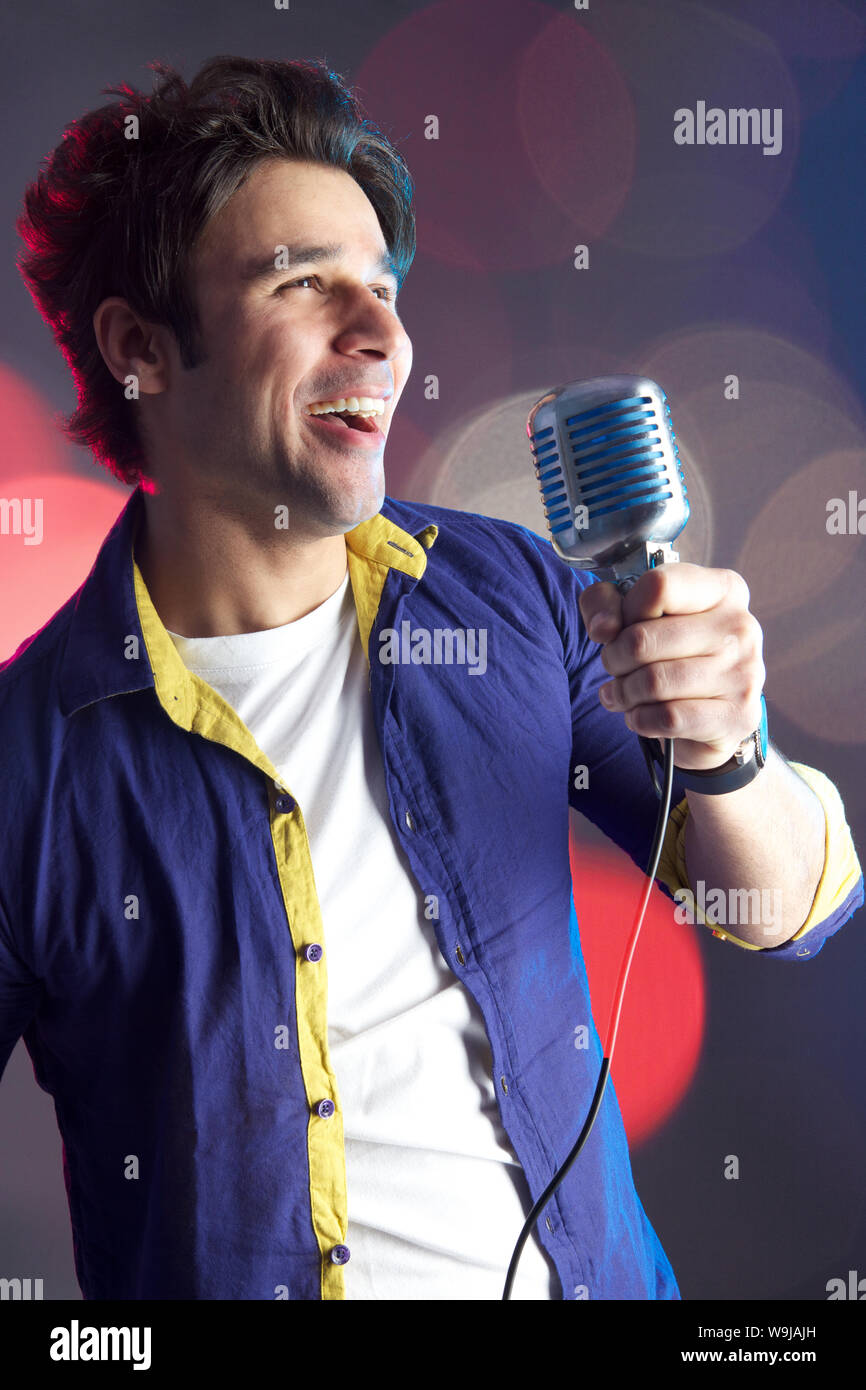 Man singing into microphone and smiling Stock Photo - Alamy