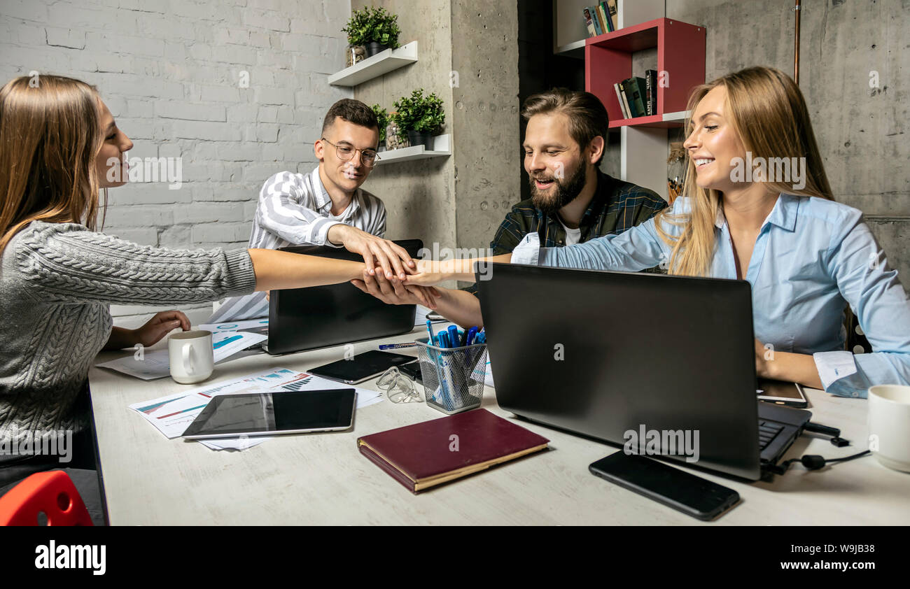 Young colleagues joining hands together as a sign of teamwork and ...