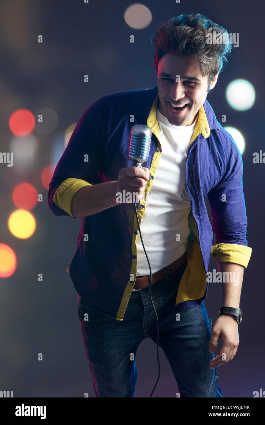 Man singing into microphone and smiling Stock Photo - Alamy