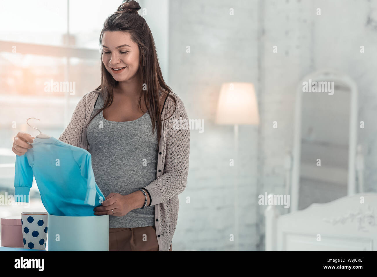 Joyful future mommy looking at nice children suit Stock Photo - Alamy