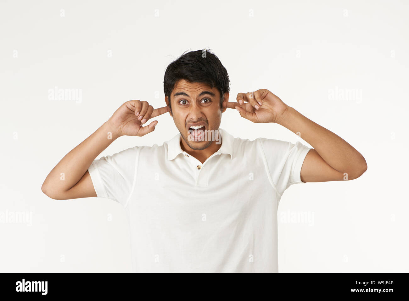 Young man with his fingers in ears and shouting Stock Photo - Alamy