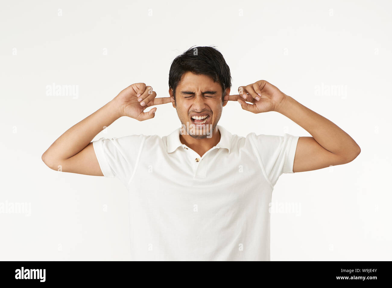 Young man with his fingers in ears Stock Photo - Alamy