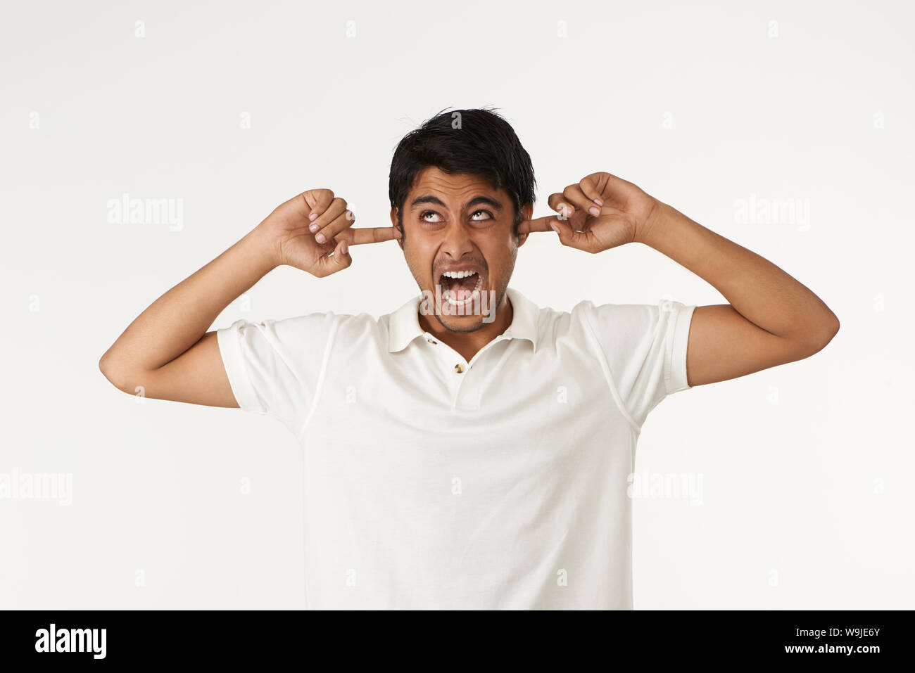 Young man with his fingers in ears and shouting Stock Photo - Alamy