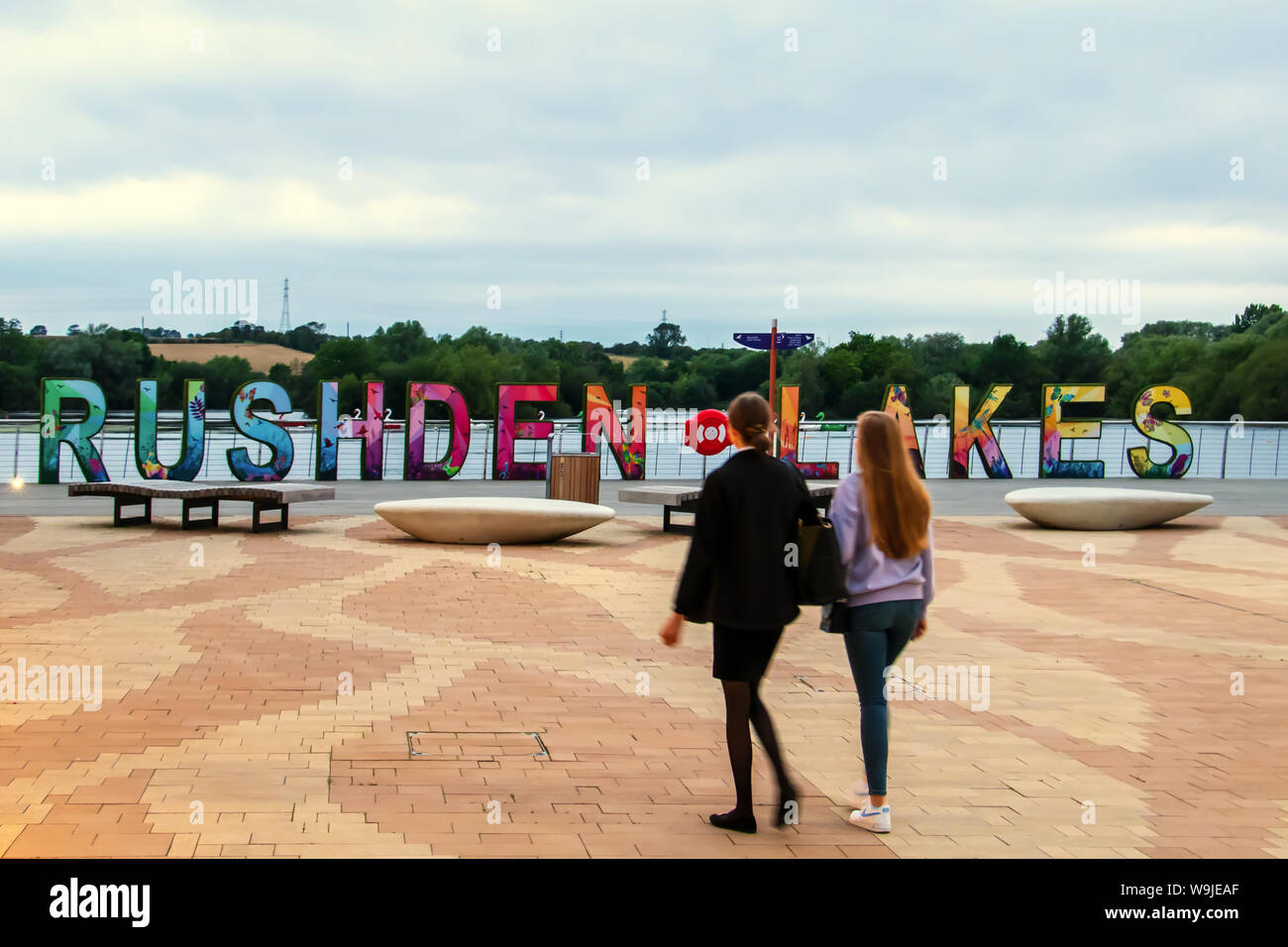Two girls walk toward the giant letters of the Rushden Lakes sign on ...