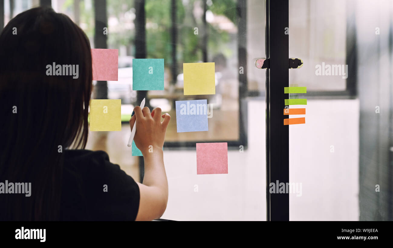Behind shot Female meeting and use post it notes to share idea her on ...