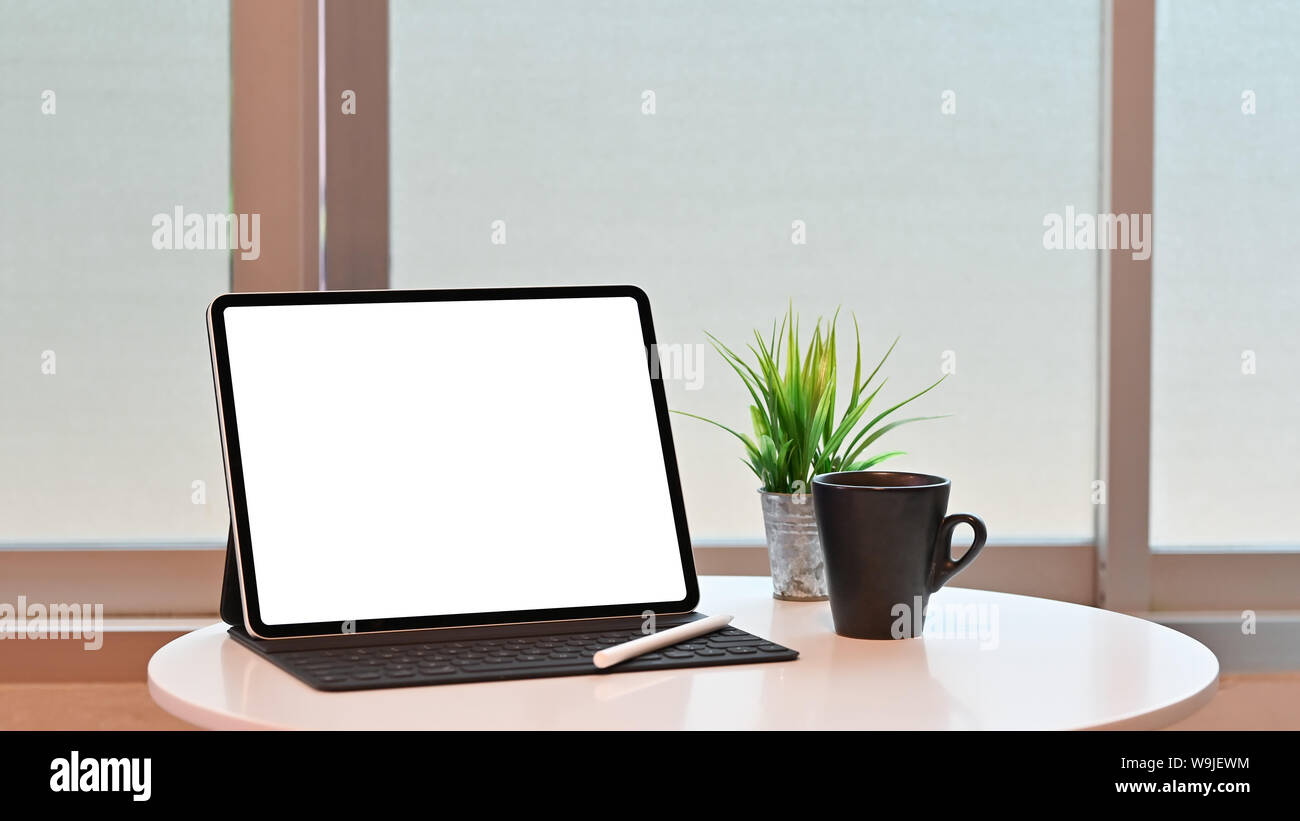 Tablet, coffee, pen and plant on table with montage screen display ...