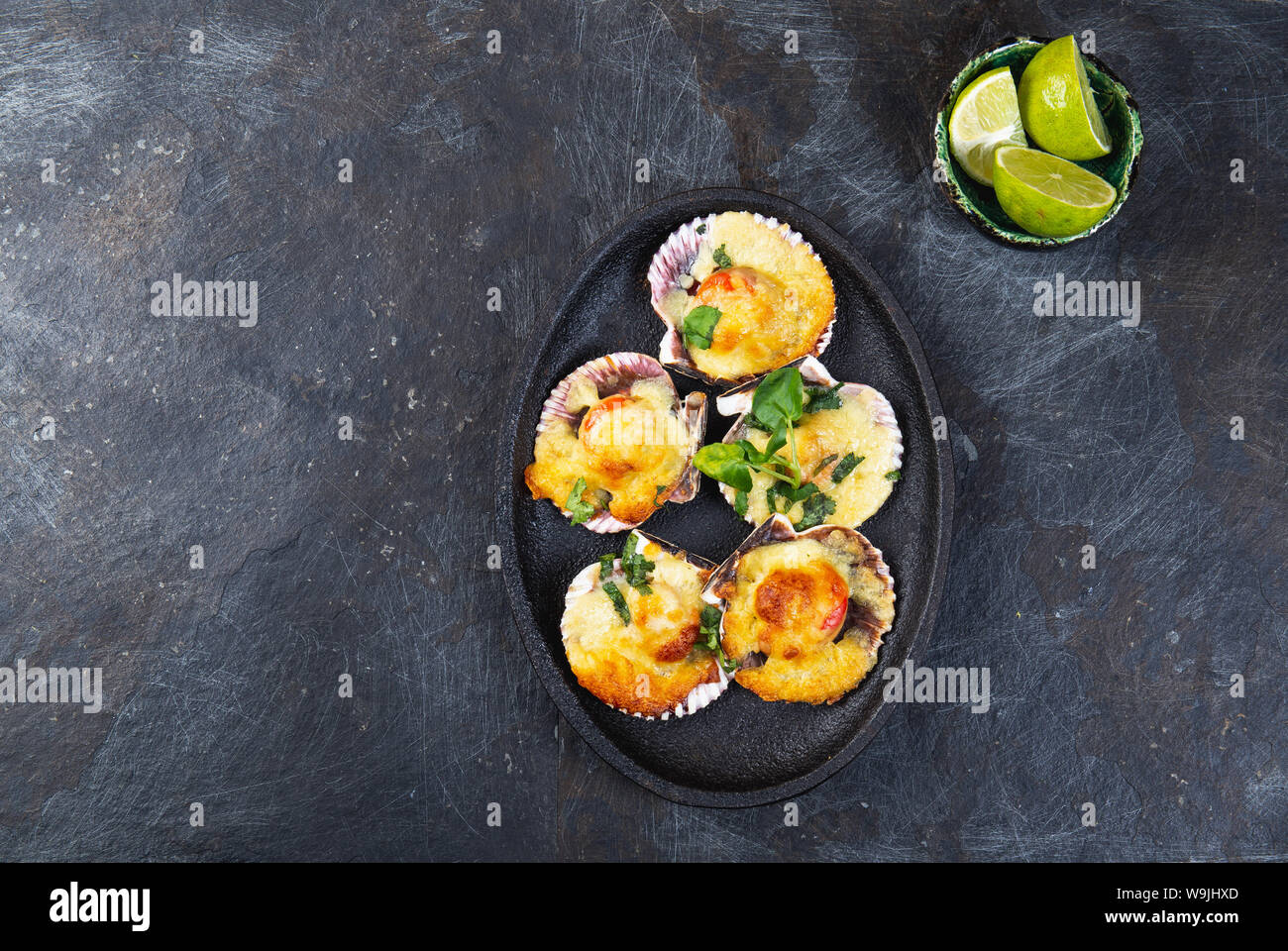 Baked seafood shellfish scallops with cheese and lemon. black ...