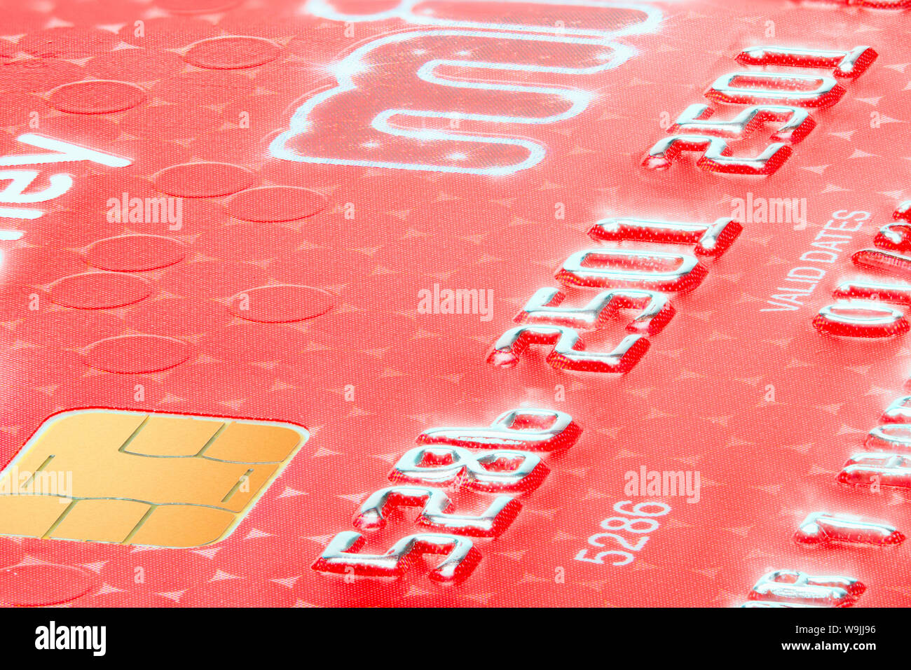 Closeup photo of a red credit card from the side, showing the golden ...