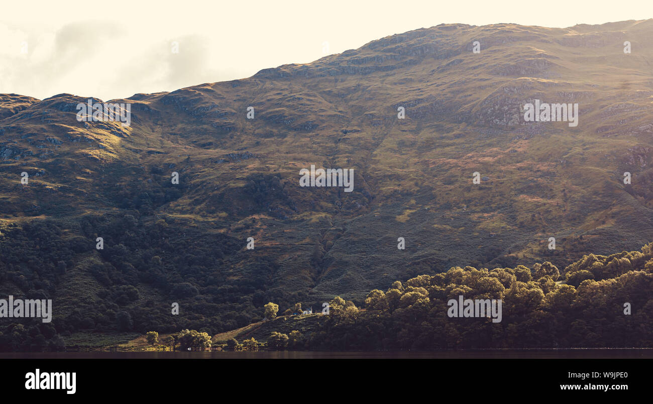 Mountains catching the late morning sun at the side of Loch Lomond on ...