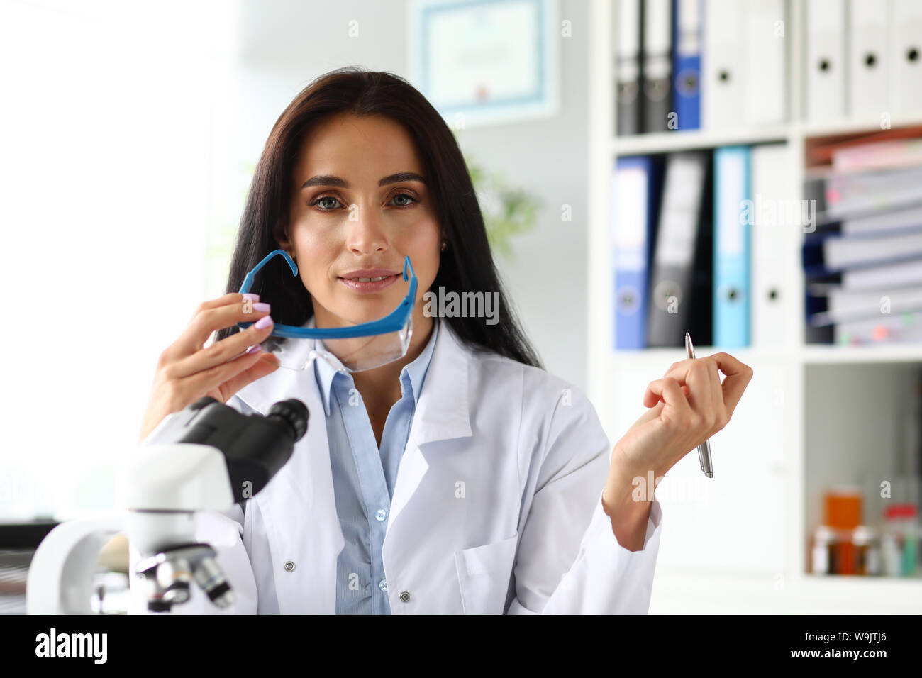 Beautiful female assistant sitting at worktable Stock Photo - Alamy