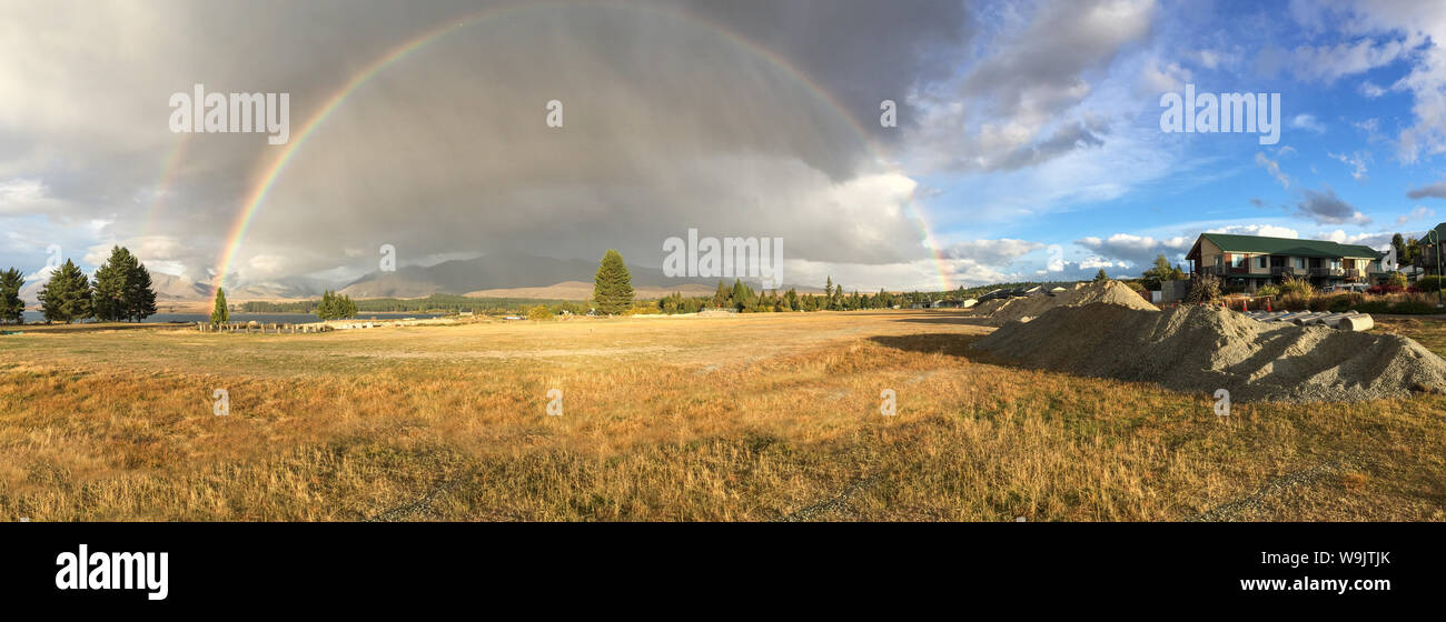 The beautiful full arch of a rainbow across a meadow in New Zealand ...