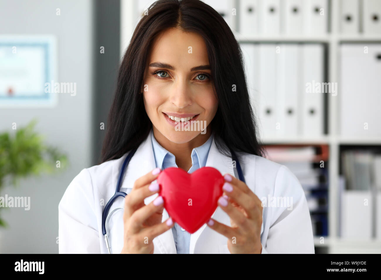 Beautiful smiling GP holding in hands red toy heart Stock Photo - Alamy