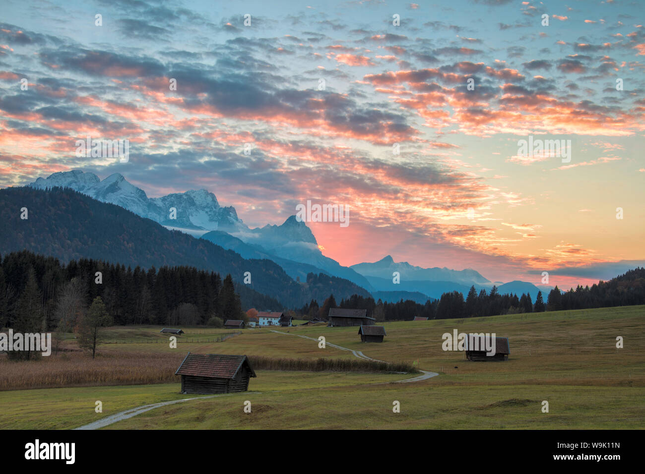 Sunset on wooden huts and meadows with the Alps in background ...