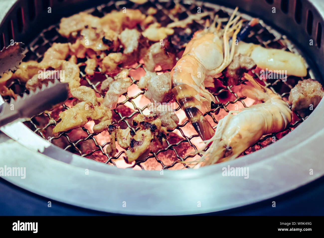 People grilling meat on a smokeless barbecue grill in a restaurant ...