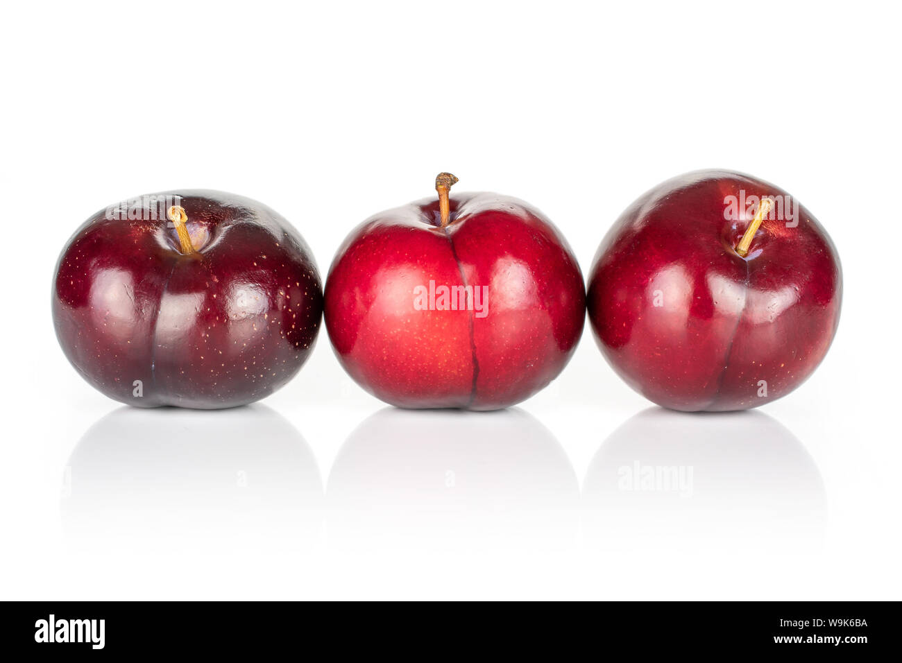 Group of three whole ripe red round plum in row isolated on white ...