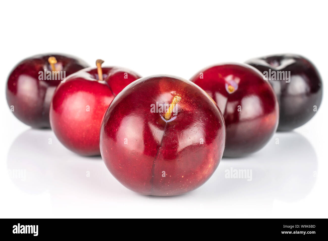 Group of five whole ripe red round plum one is in the front arranged ...