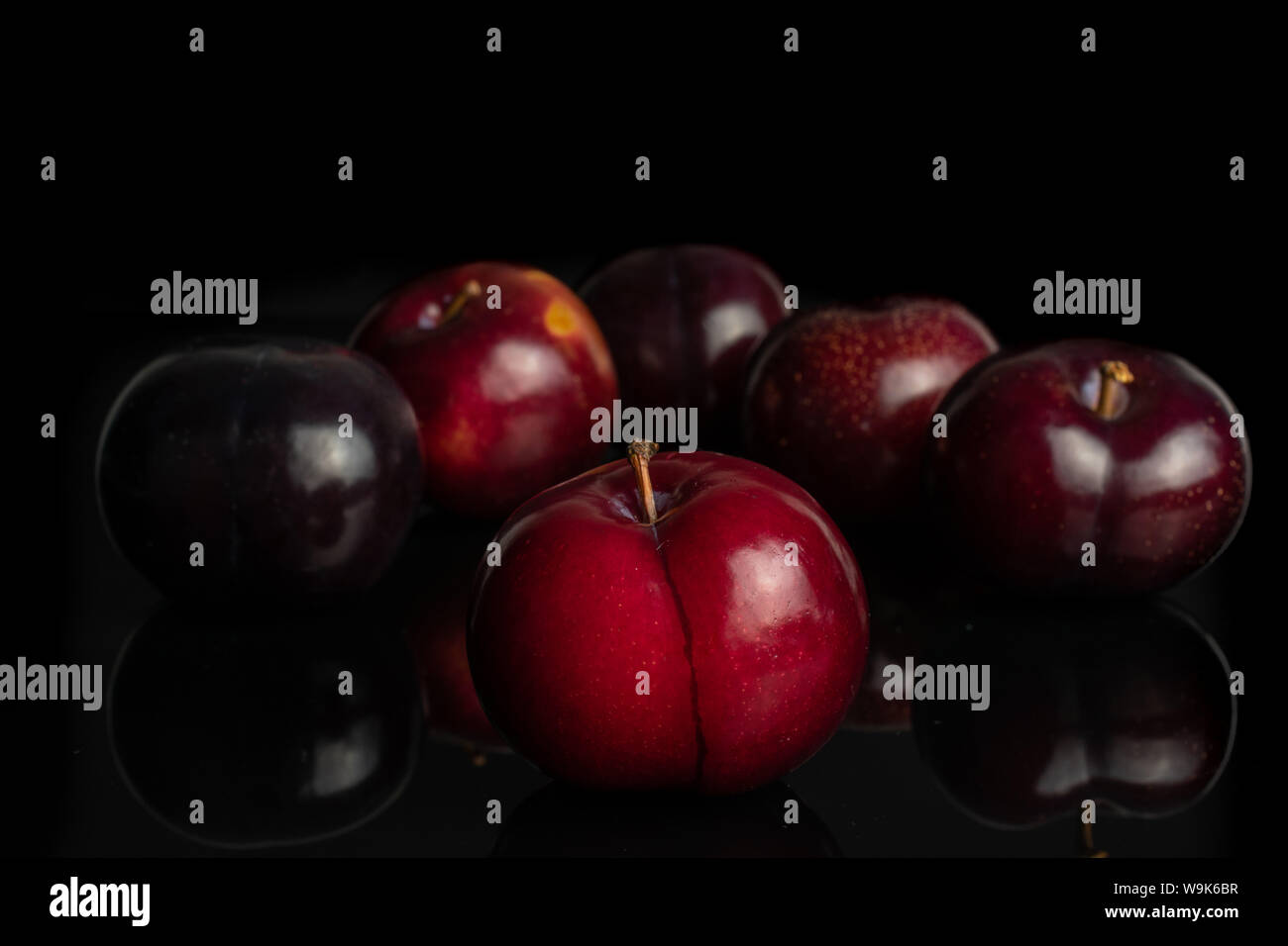 Group of six whole ripe red round plum arranged symmetrically isolated ...