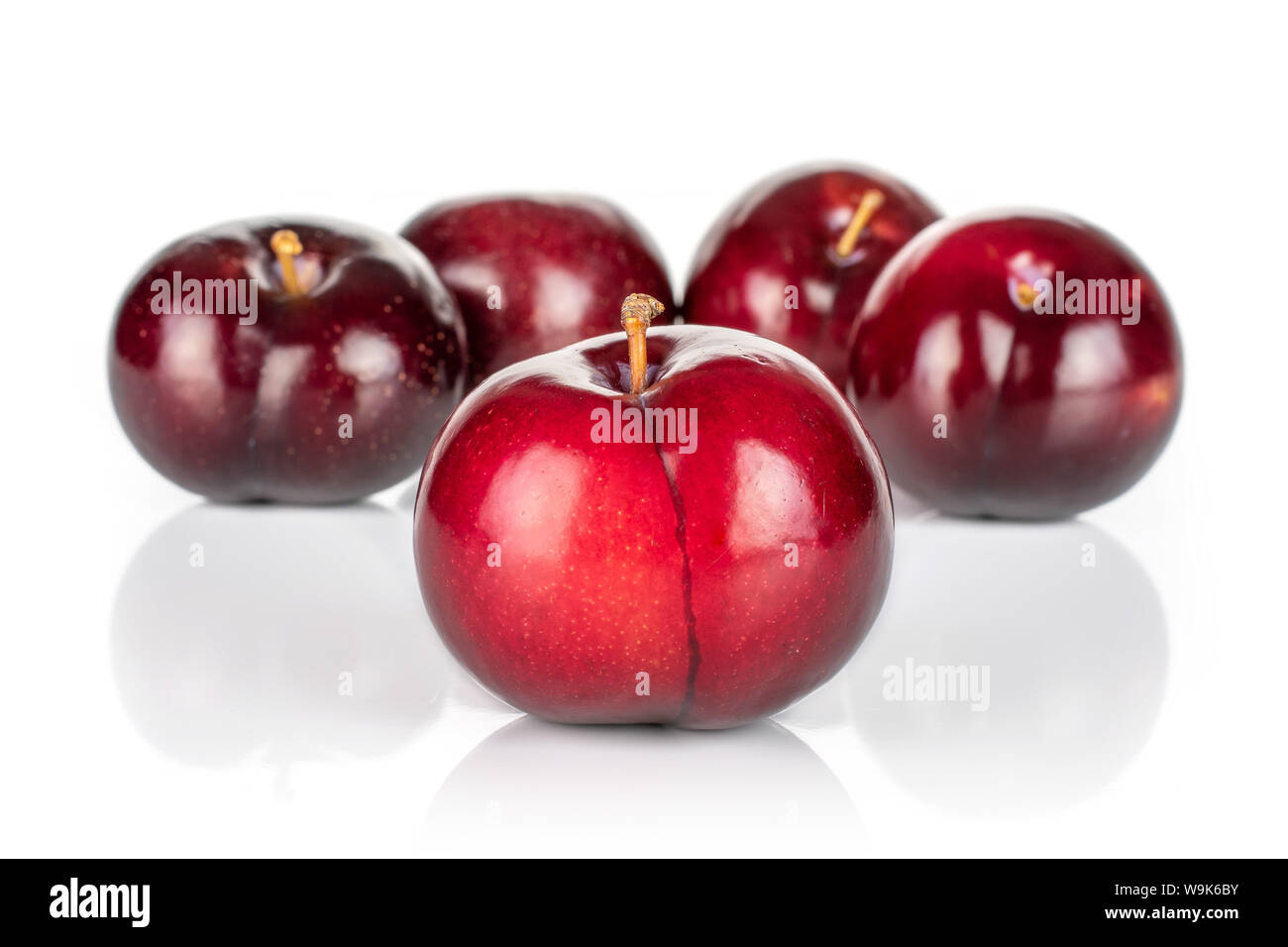 Group of five whole ripe red round plum arranged symmetrically isolated ...