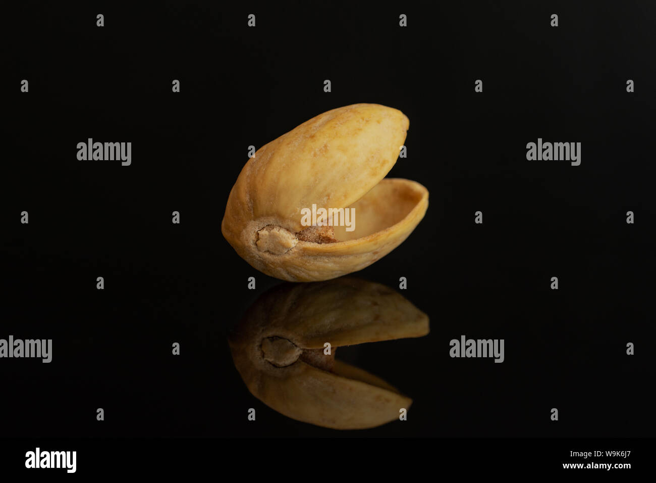 One piece of shell of ripe green pistachio in closeup isolated on black ...