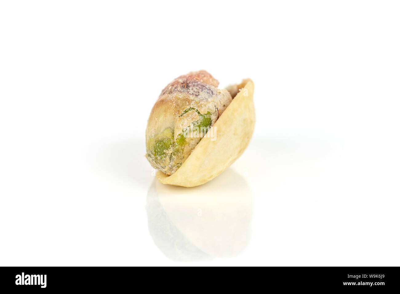 One whole ripe green pistachio half open in closeup isolated on white ...