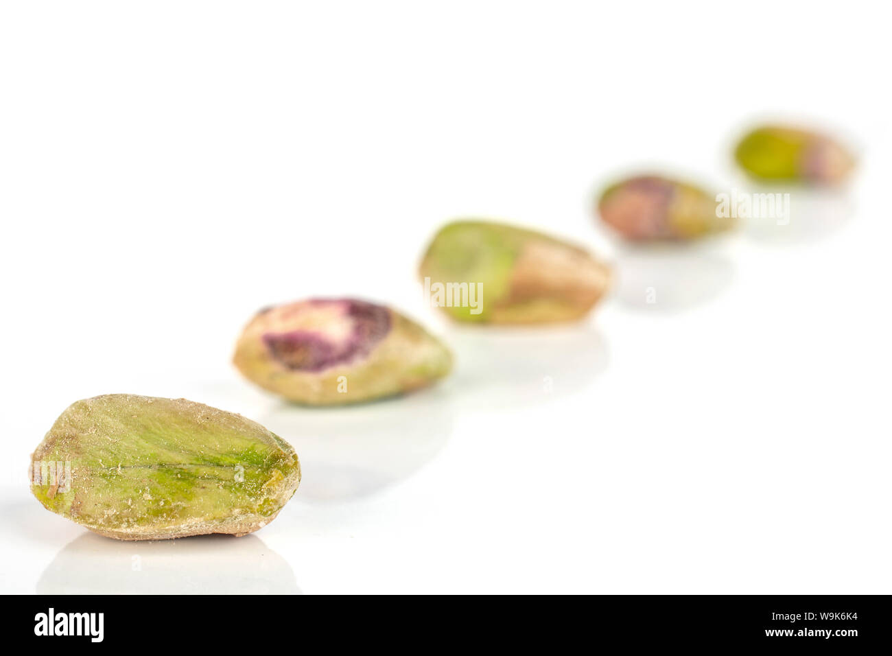 Group of five whole ripe green pistachio in closeup placed diagonally ...
