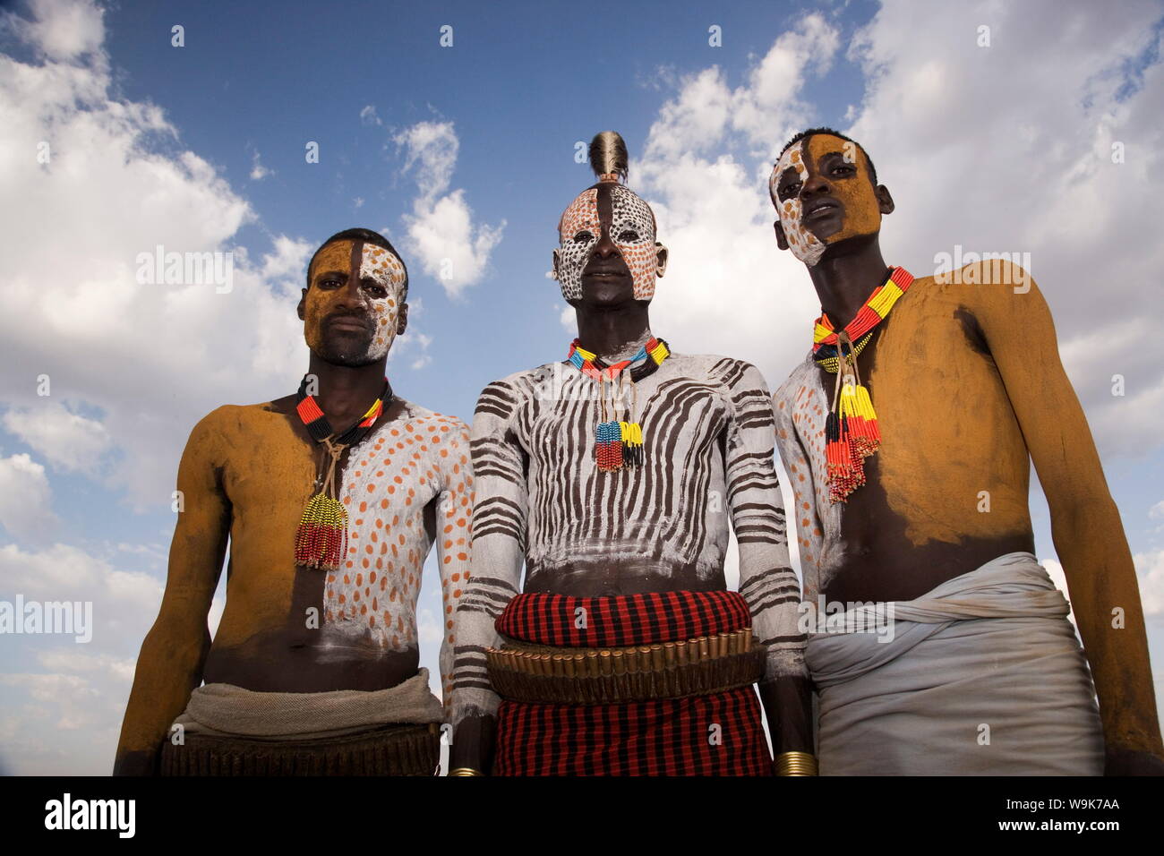Portrait of three Karo tribesmen with faces and bodies painted with ...