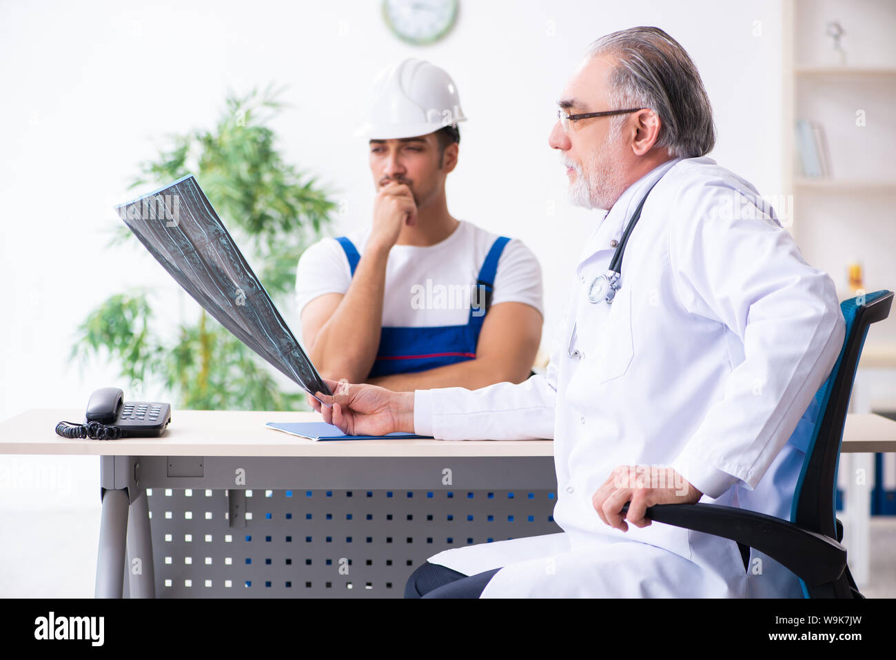 The young male contractor visiting old doctor Stock Photo - Alamy