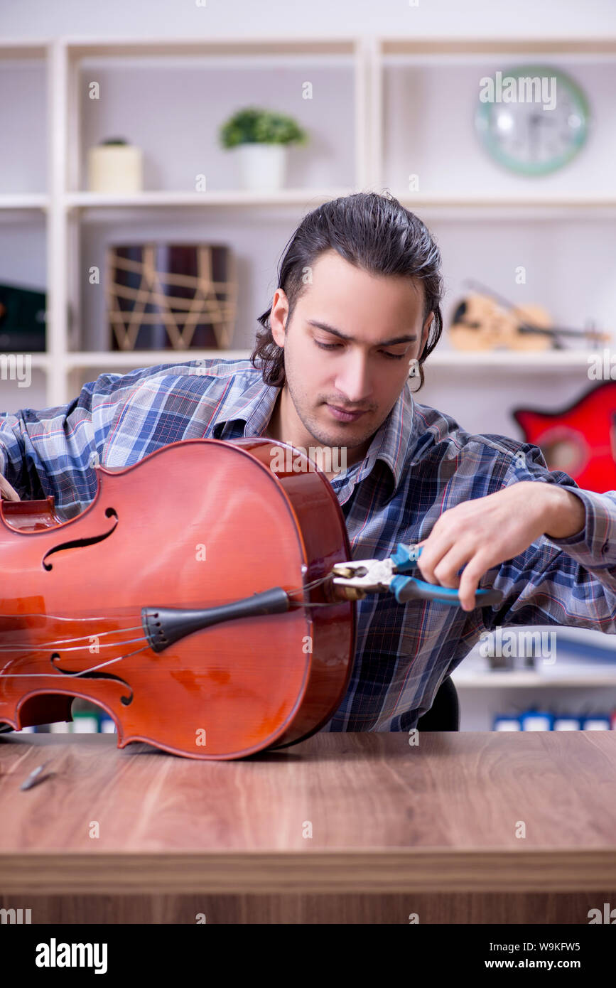 The young handsome repairman repairing cello Stock Photo - Alamy