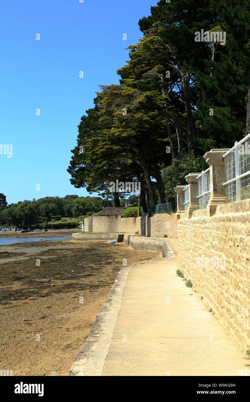 Coastal footpath and wall with sea at low tide at Plage, Kerlann ...