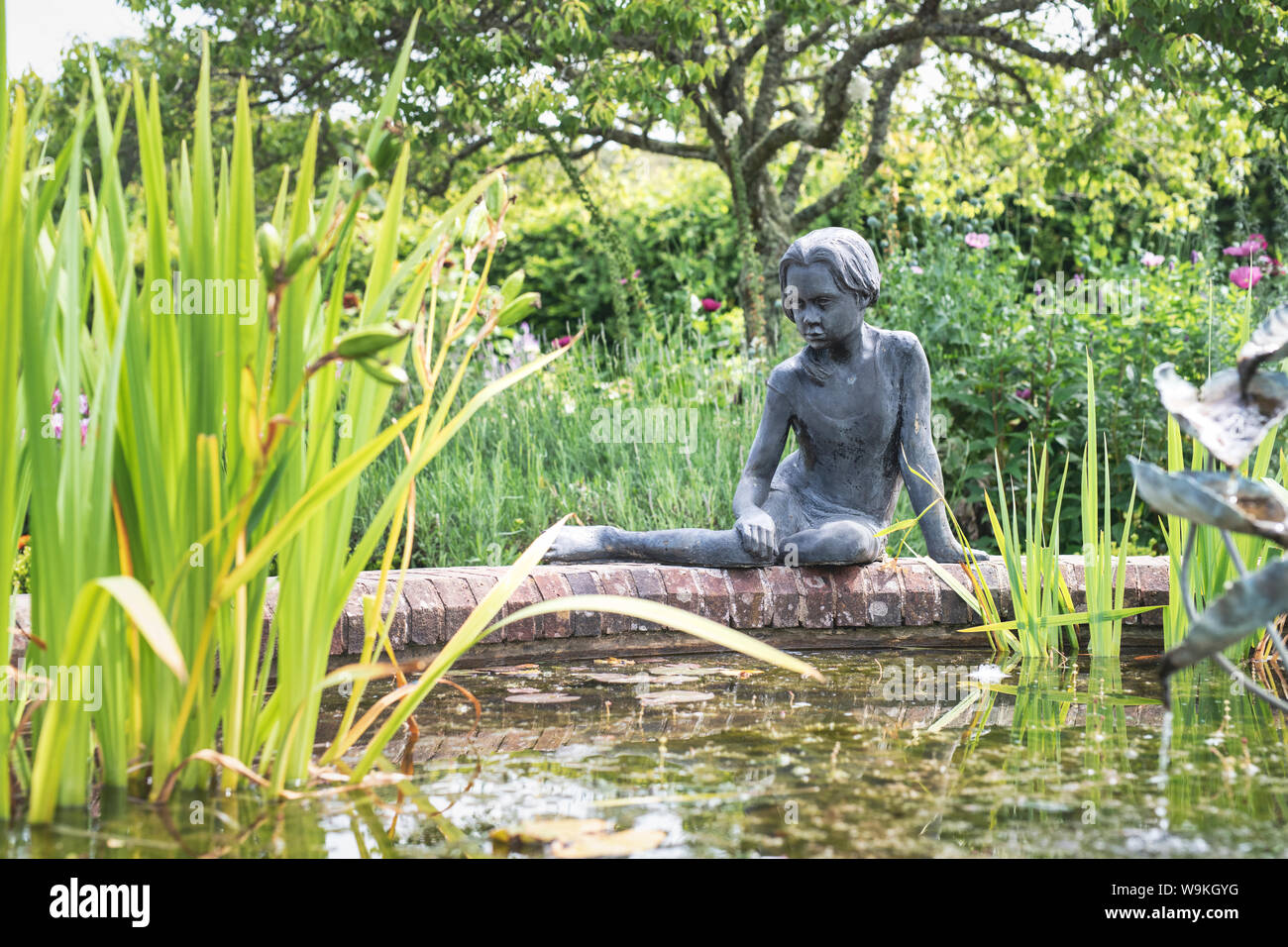Bronze Statue of a young girl sitting next to a garden pond at RHS ...