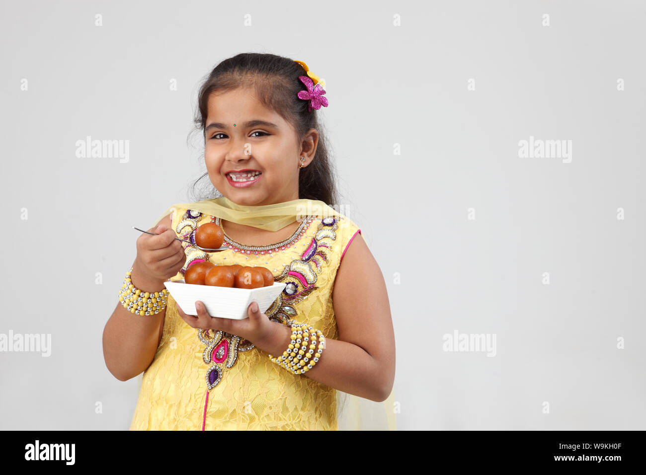 Girl eating gulab jamun and smiling Stock Photo - Alamy
