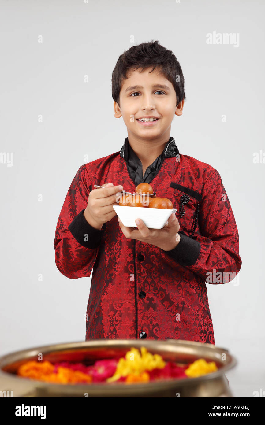 Boy eating gulab jamun and smiling Stock Photo - Alamy