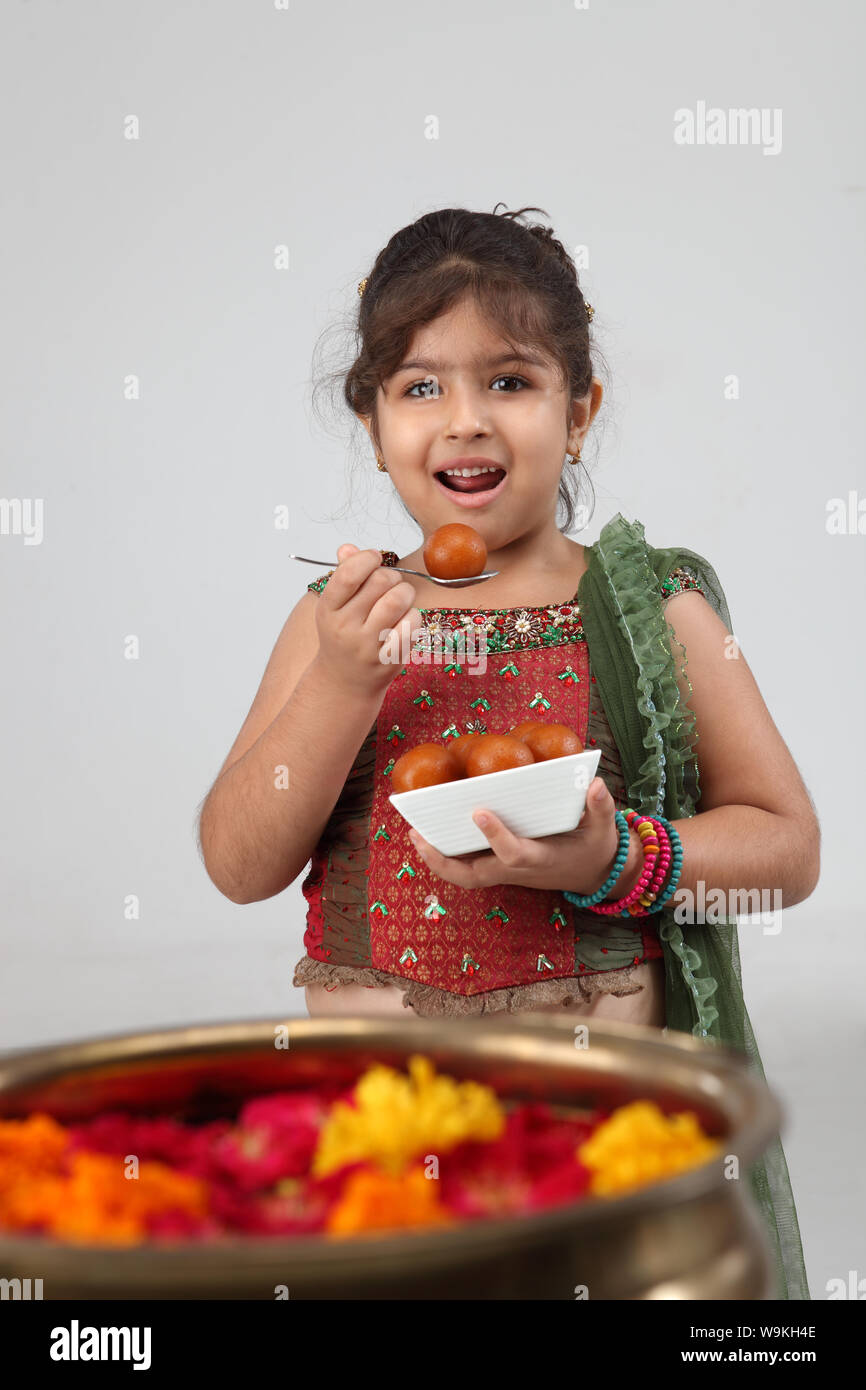 Girl eating gulab jamun and smiling Stock Photo - Alamy