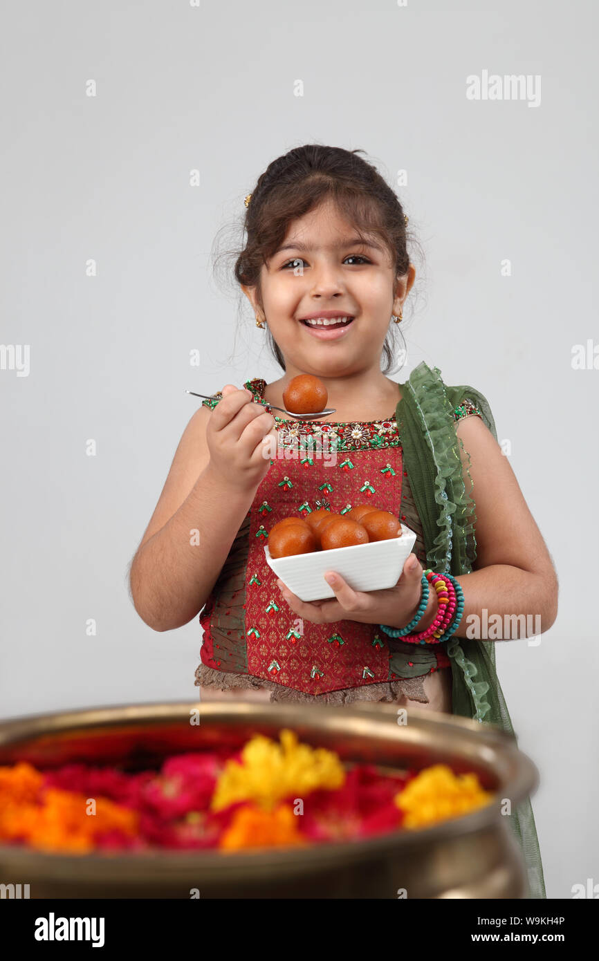 Girl eating gulab jamun and smiling Stock Photo - Alamy