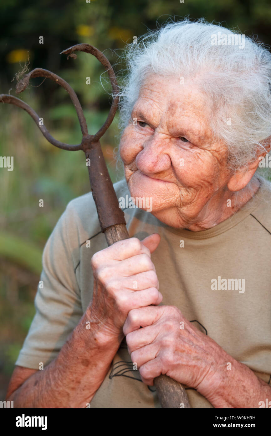 Closeup portrait of an old woman with gray hair holding a rusty ...