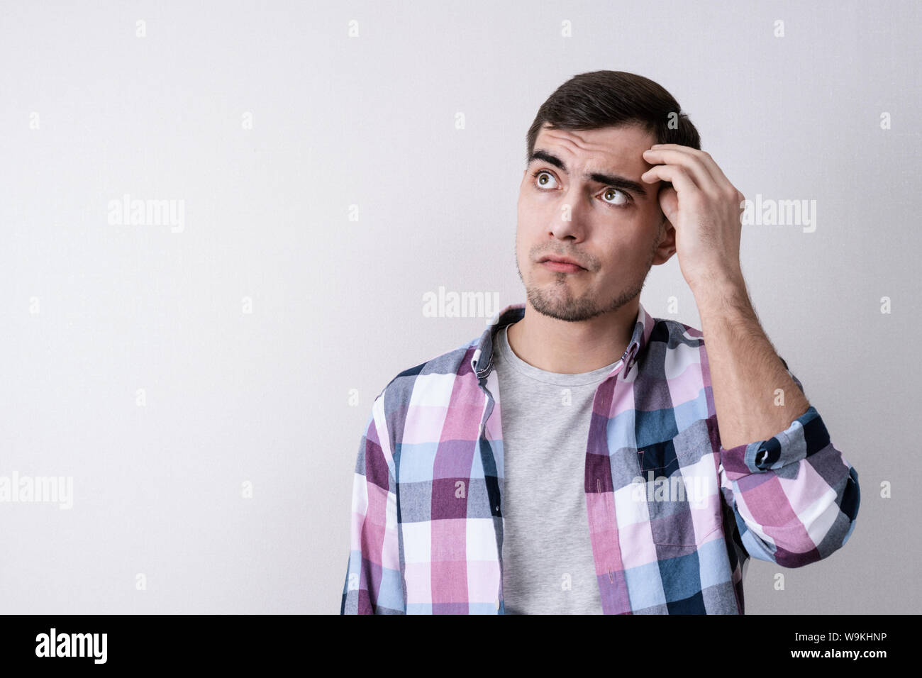 Portrait of brooding young man on gray background with copy of space ...