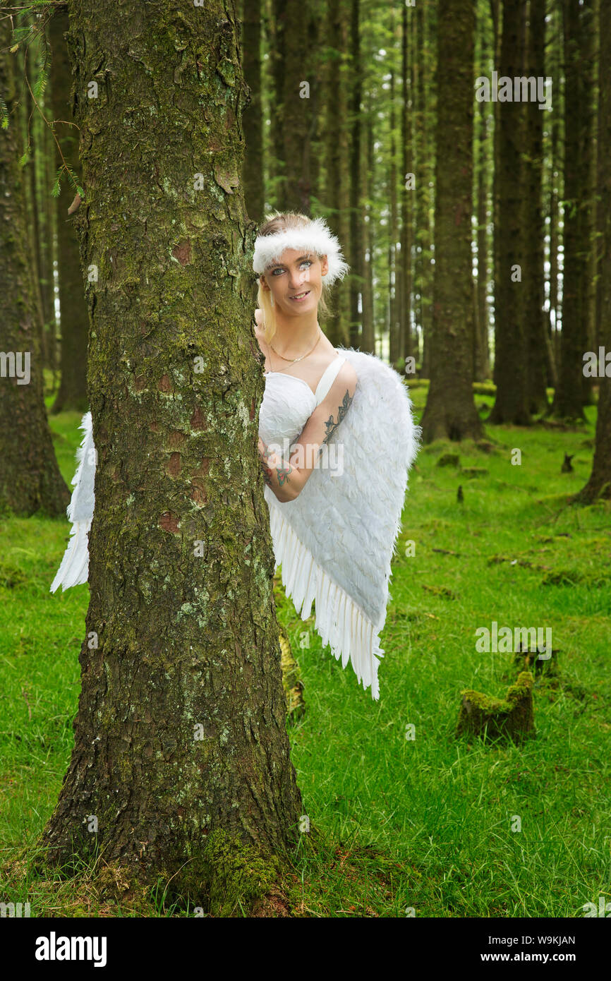 A blonde model wearing angel wings in a forest Stock Photo - Alamy