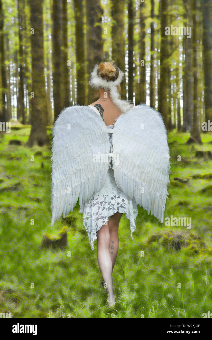 A blonde model wearing angel wings in a forest Stock Photo - Alamy