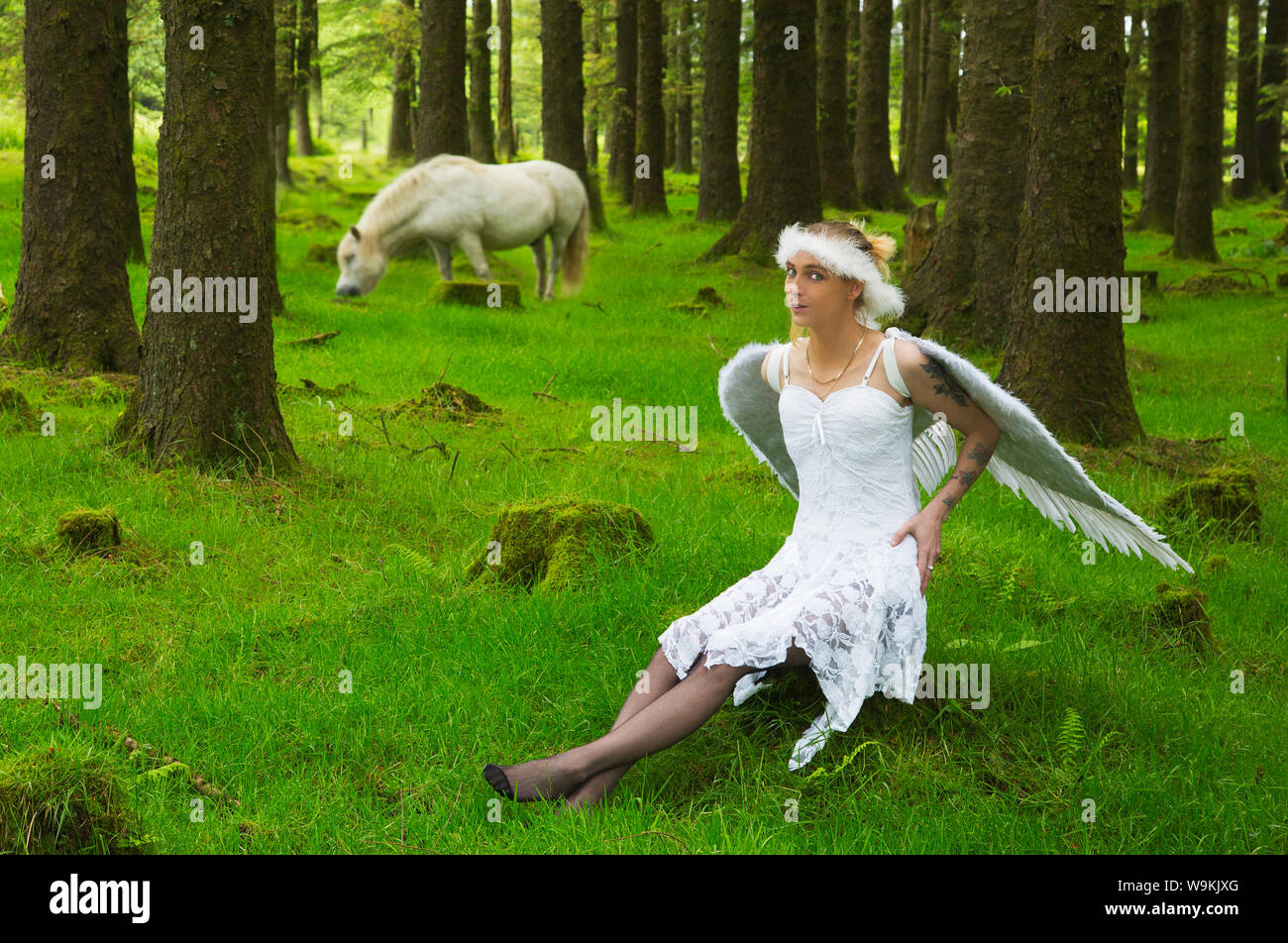 A blonde model wearing angel wings in a forest Stock Photo - Alamy