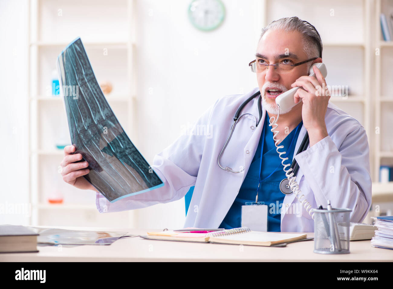 The old male doctor working in the clinic Stock Photo - Alamy