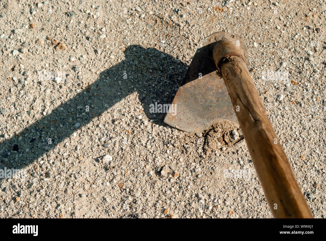 blade of a primitive hoe, trying to pierce dry hard barren sandy soil ...