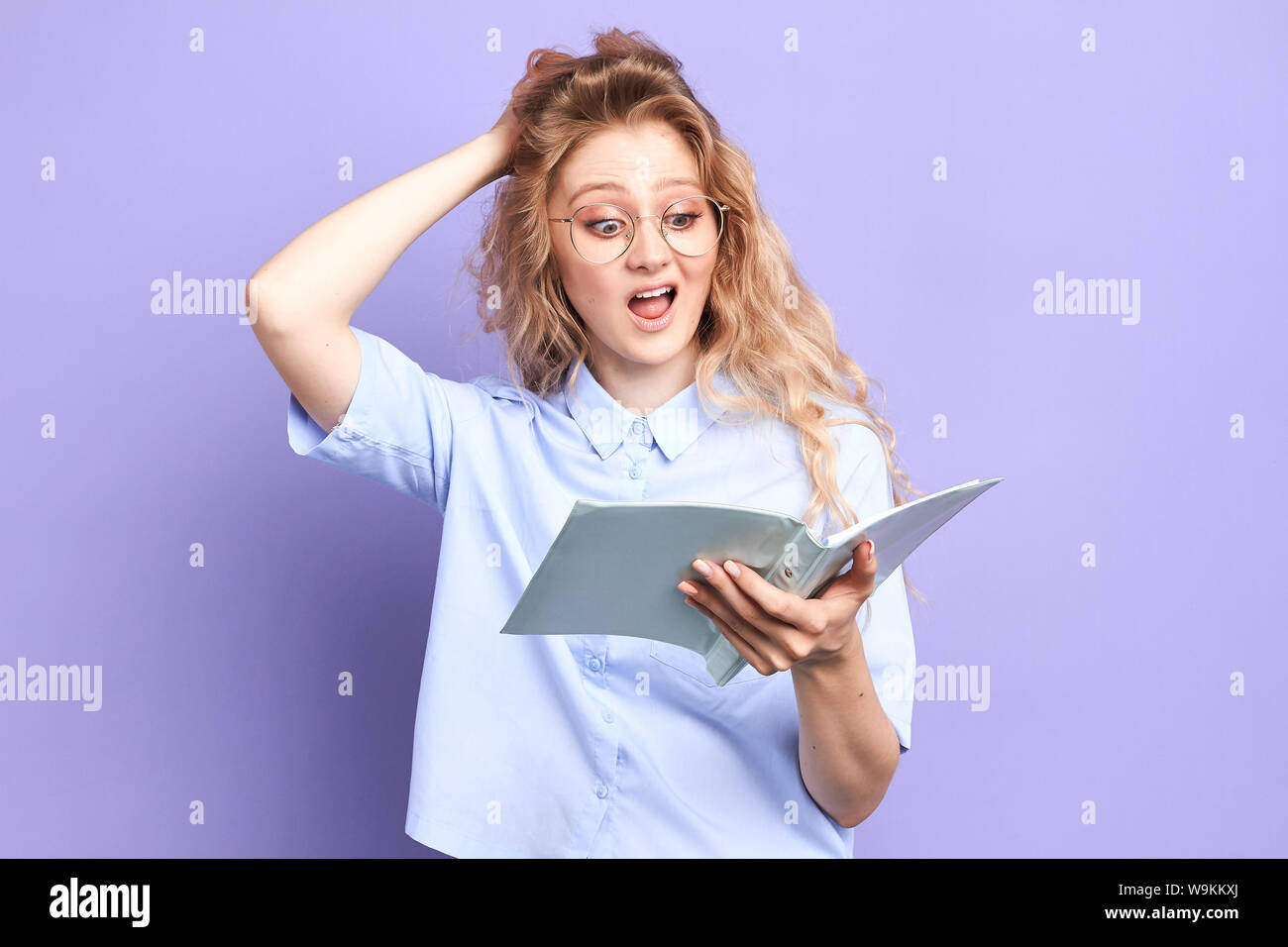 Puzzled funny student has contemplative expression, holds notebook ...