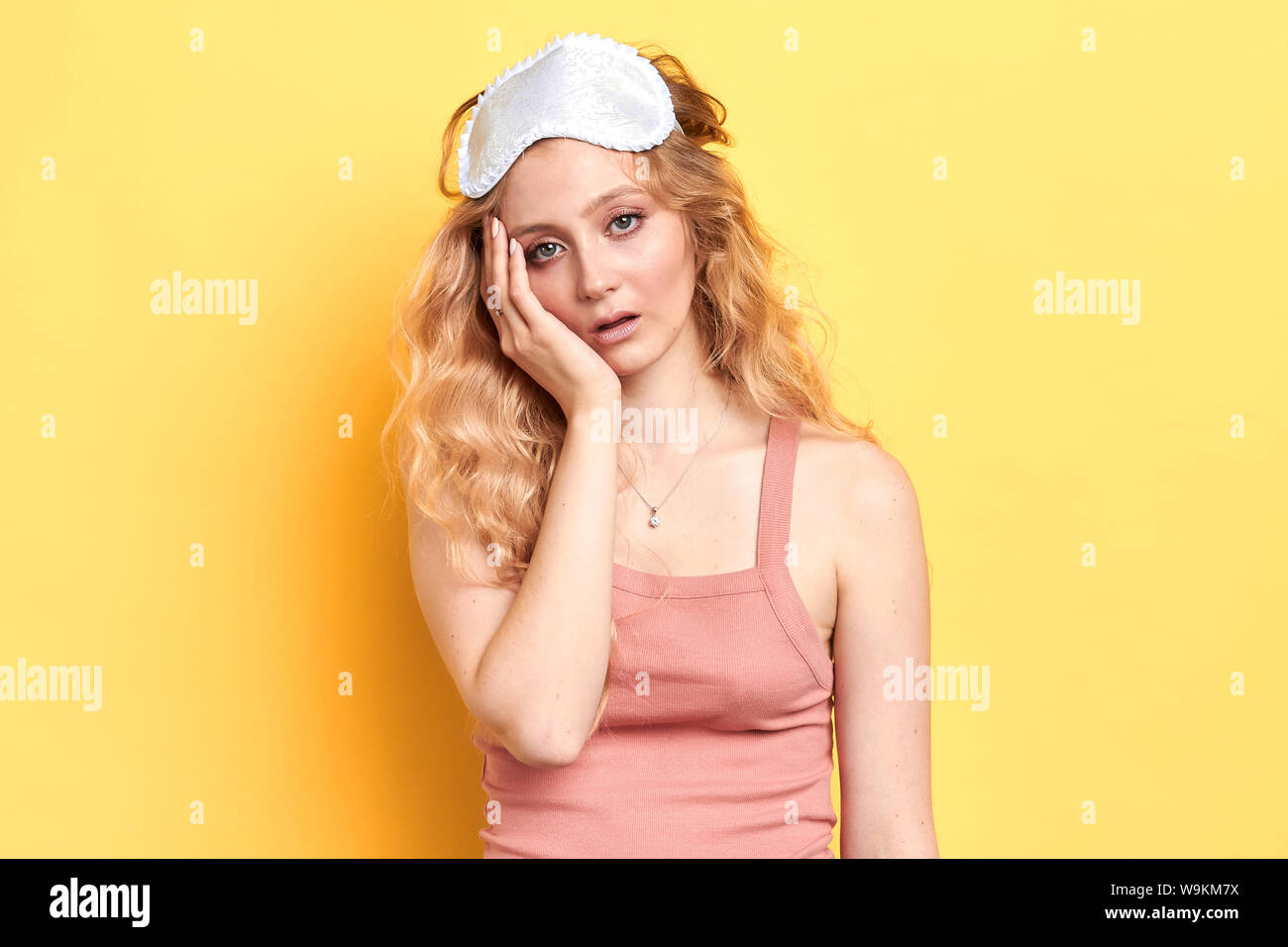 Tired sleepy woman in pink top touching her face with palm, has sad ...