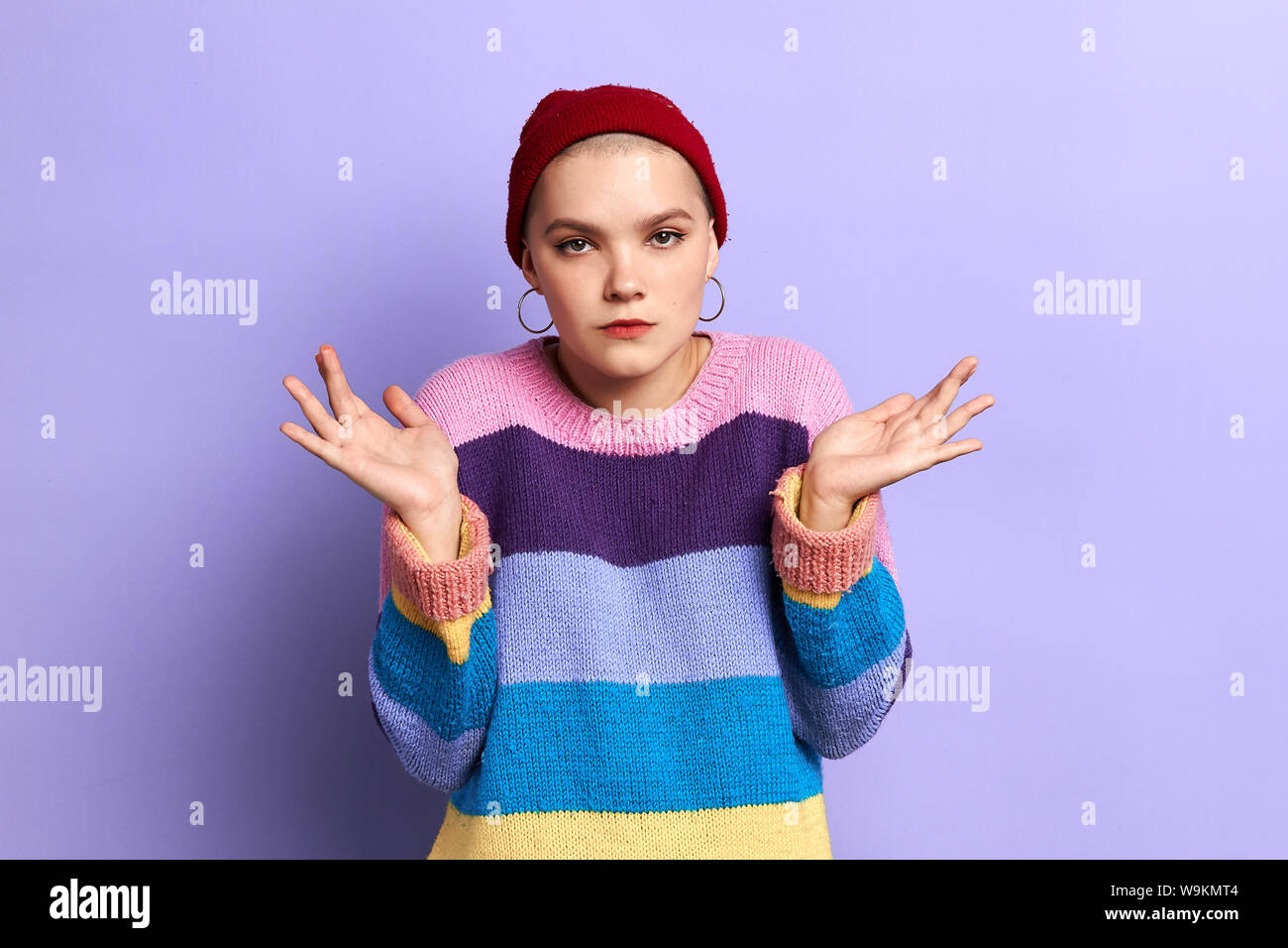 .Young serious woman expresses clueless and confused emotion with arms ...