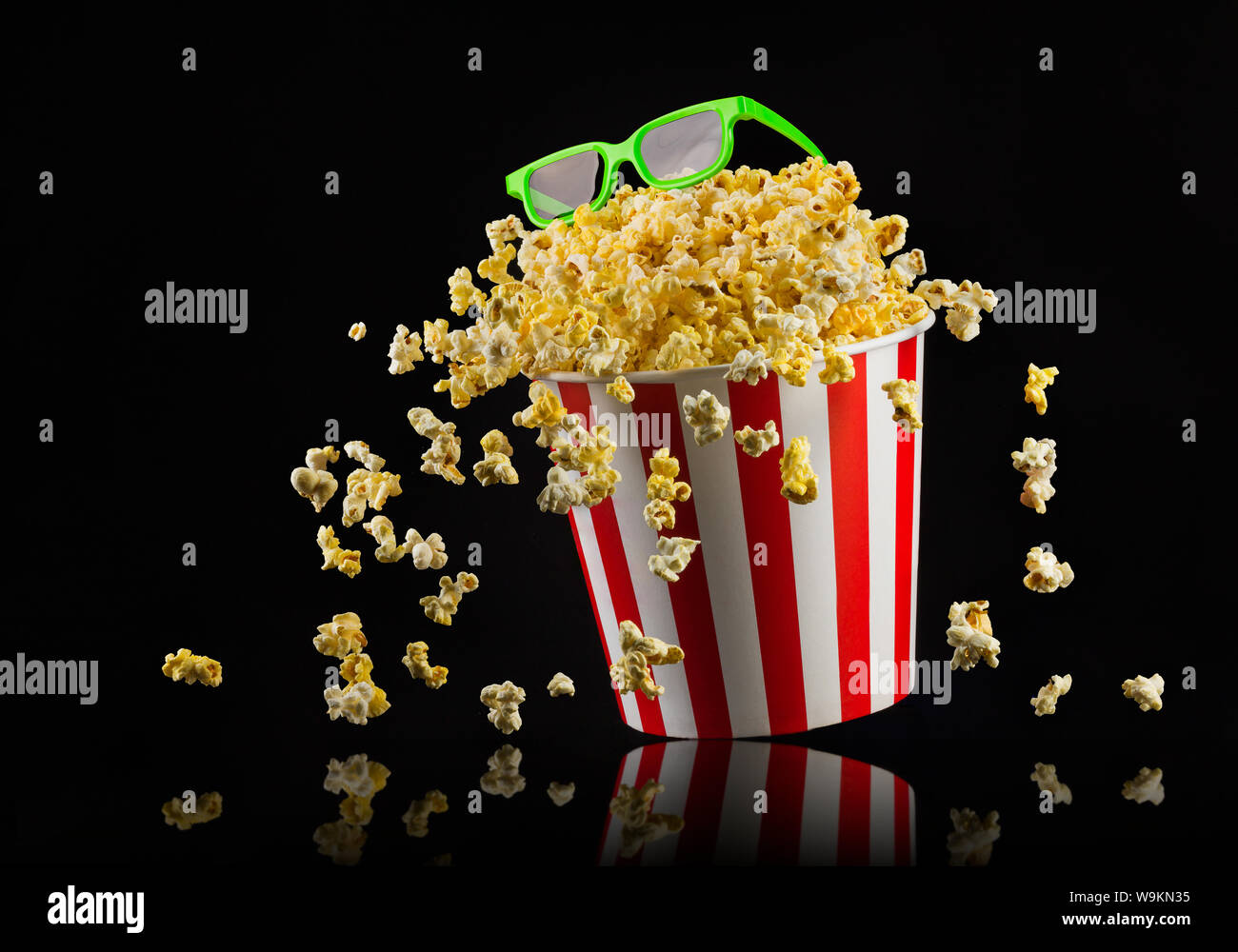 Flying popcorn from striped bucket isolated and 3d glasses on black ...