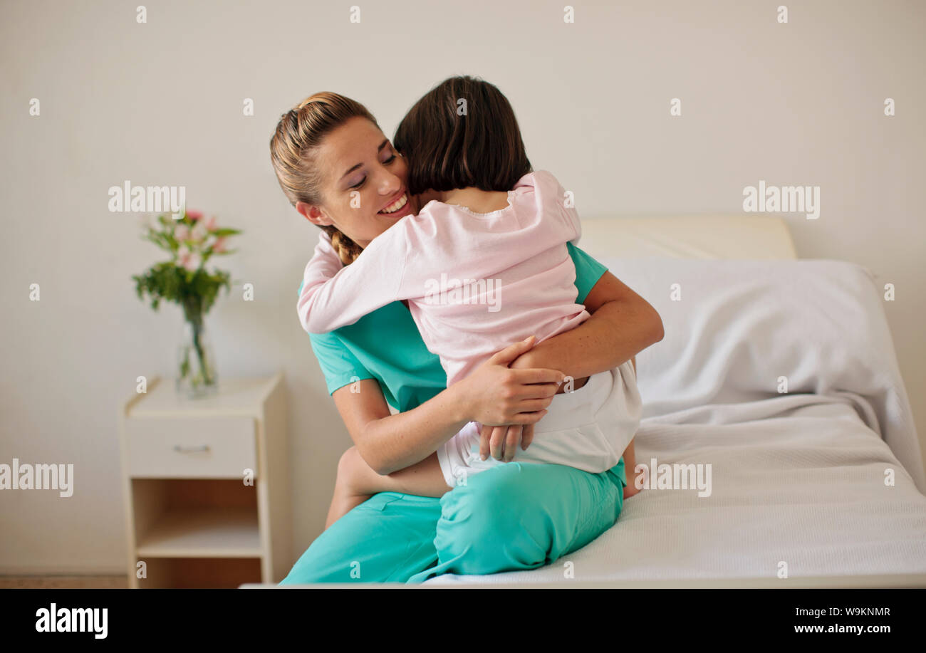 Young girl hugging nurse in hospital room Stock Photo - Alamy